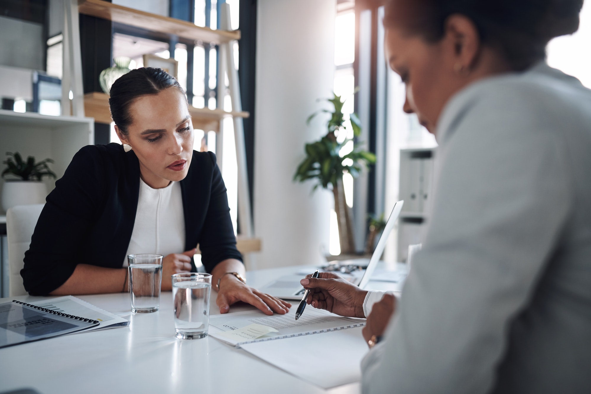Cropped shot of two attractive young businesswomen filling out ...